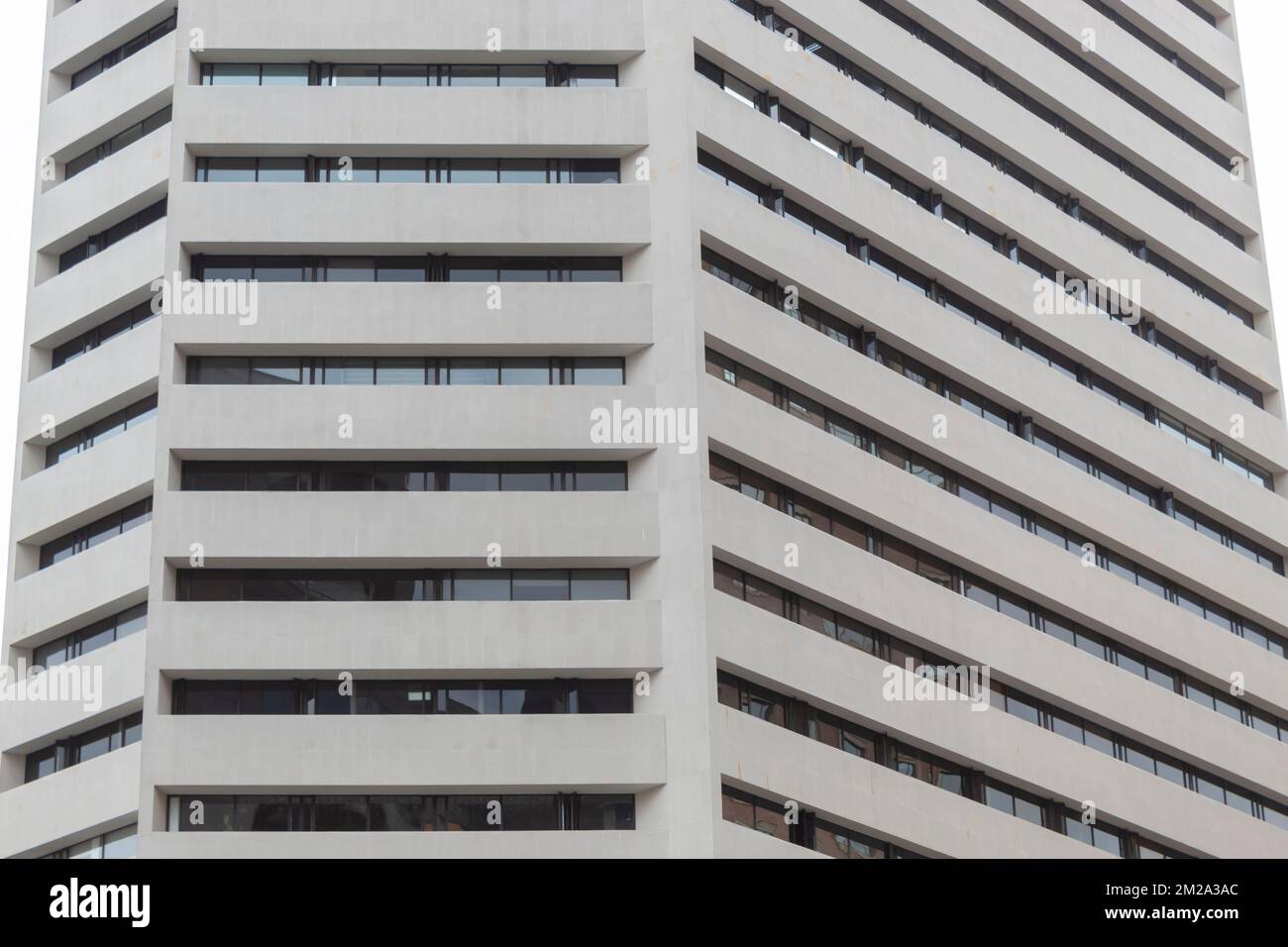 Closeup to an old white building corner with dark rectangle windows ...