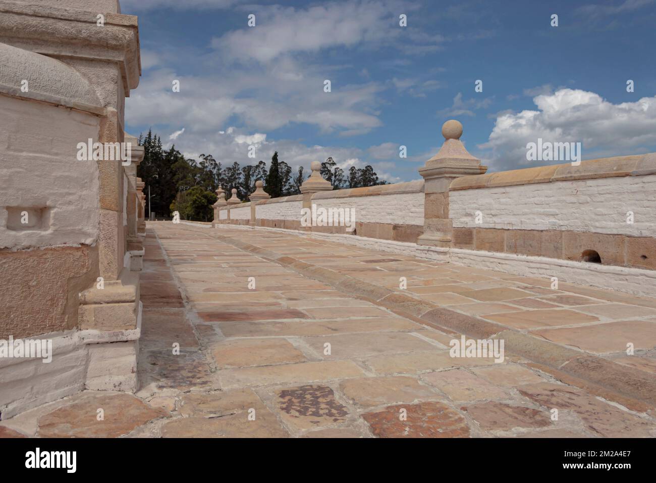 Ground view of a antique and colonial stone bridge with green trees and ...