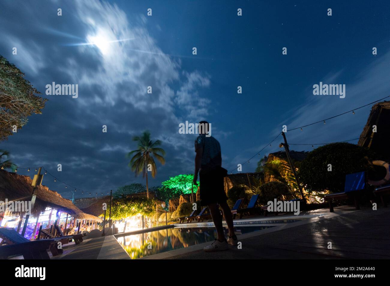 Young man looking up night starry night with full moon at caribbean ...