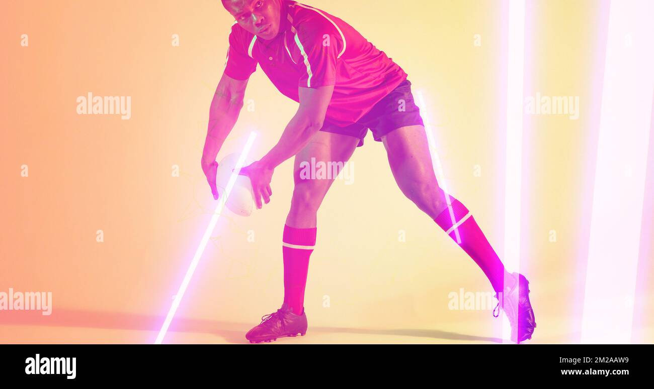 Low section of african american rugby player holding ball by glowing ...
