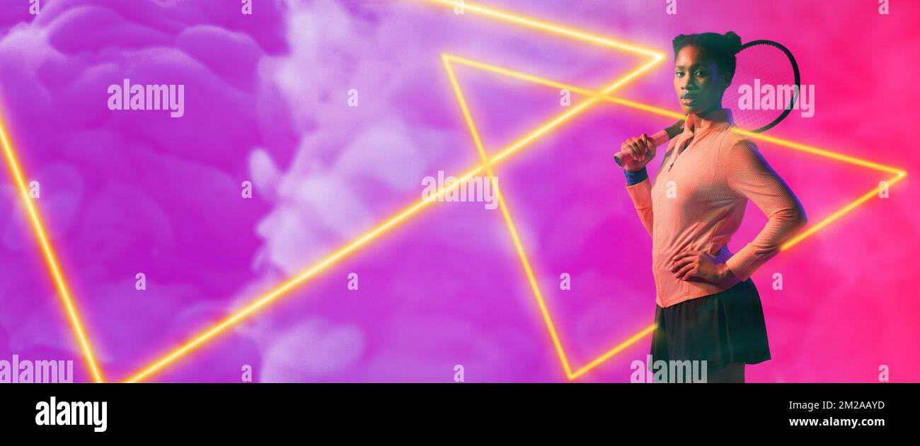 African american female tennis player holding racket by illuminated ...