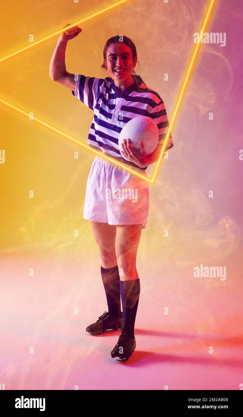 Cheerful caucasian female rugby player with ball raising hand by ...