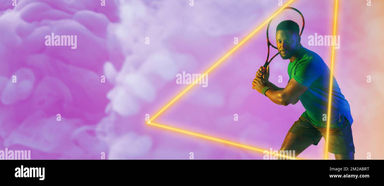 African american male tennis player holding racket by illuminated ...