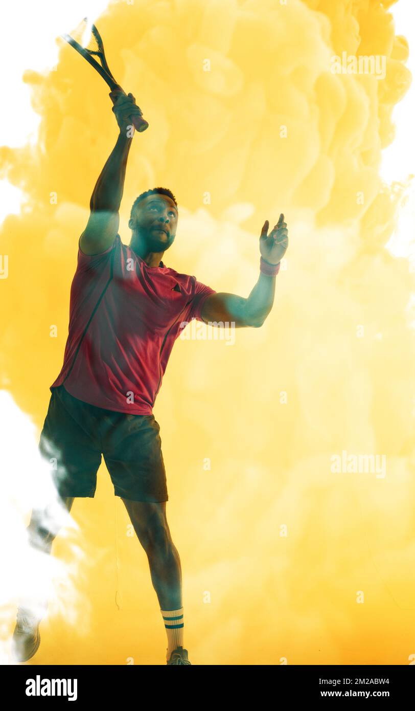 African american male tennis player hitting with racket over yellow ...