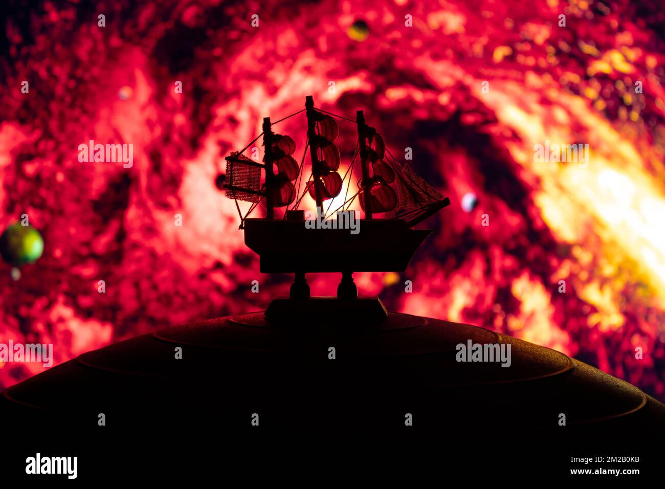 Beautiful boat toy over a blue balll with blurred red space vortex ...