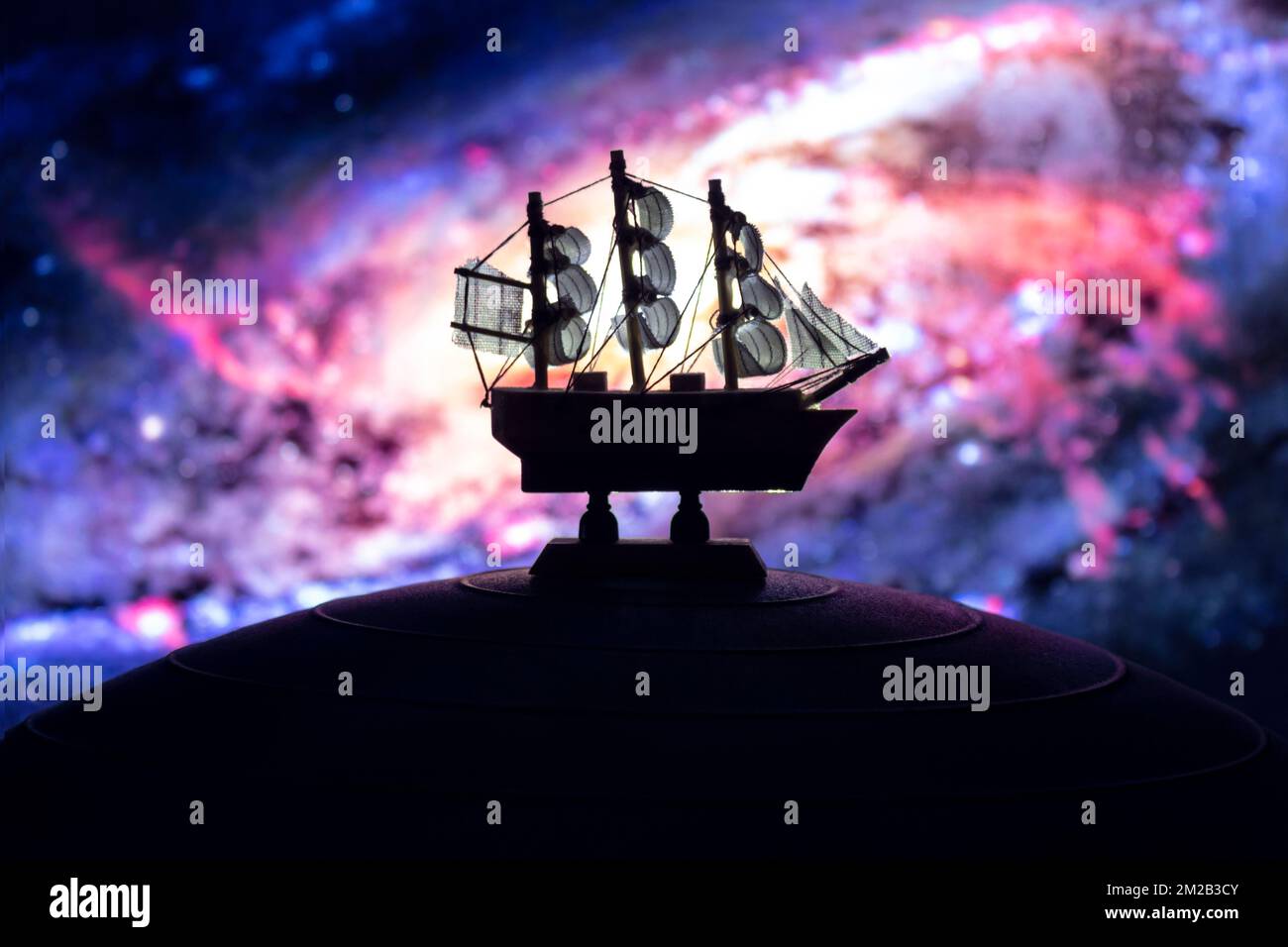 Beautiful boat toy over a blue balll with blurred multicolor andromeda ...