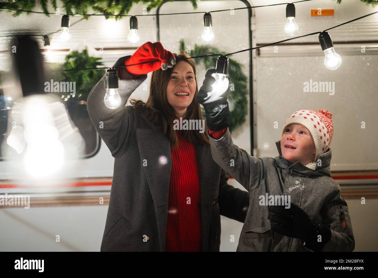 Caucasian woman and son decorate camper for christmas. Happy family ...