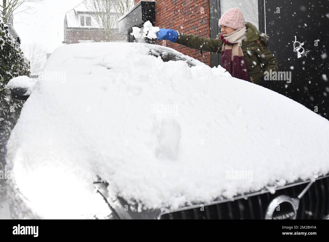Illustration picture shows A woman clears snow from the windscreen of her car as cold ...