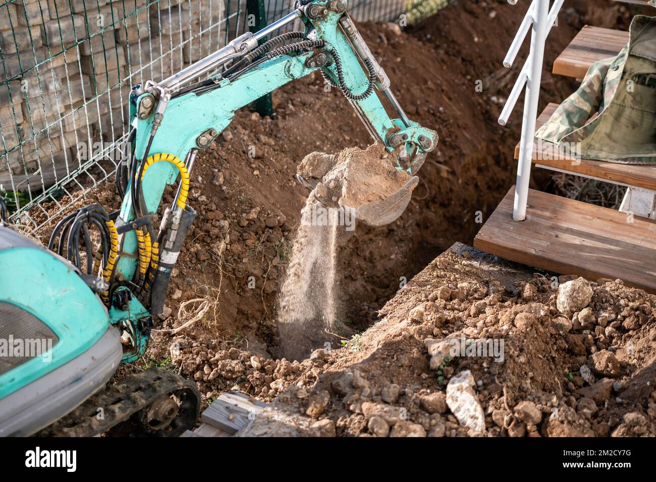 Mini excavator digs a trench to lay pipes. Close up of an excavator ...