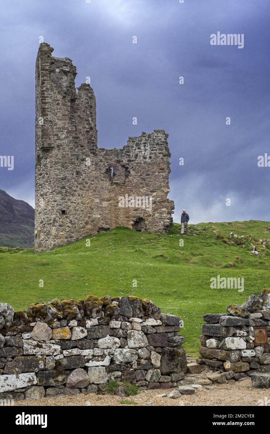 Tourist visiting 16th century Ardvreck Castle ruin at Loch Assynt in ...