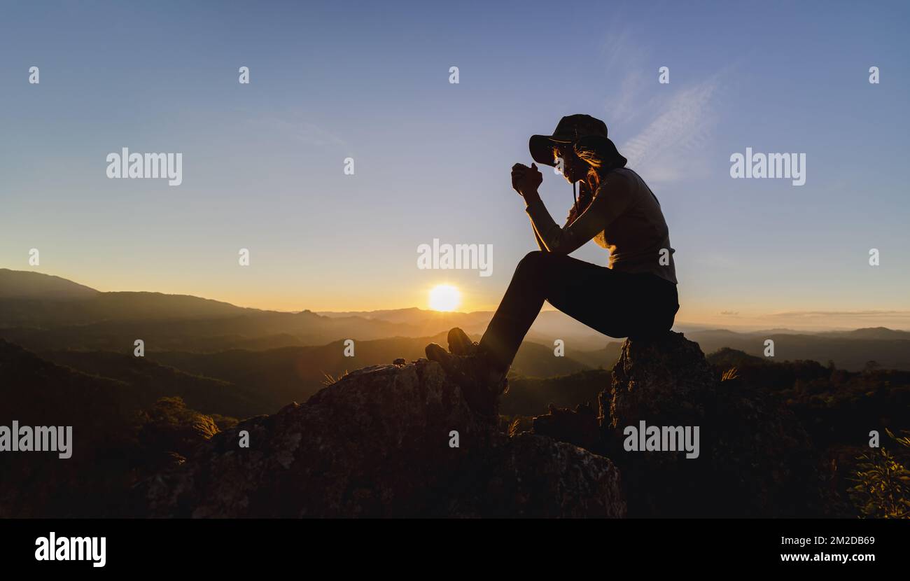 Silhouette of christian young woman praying at sunrise, Freedom and ...