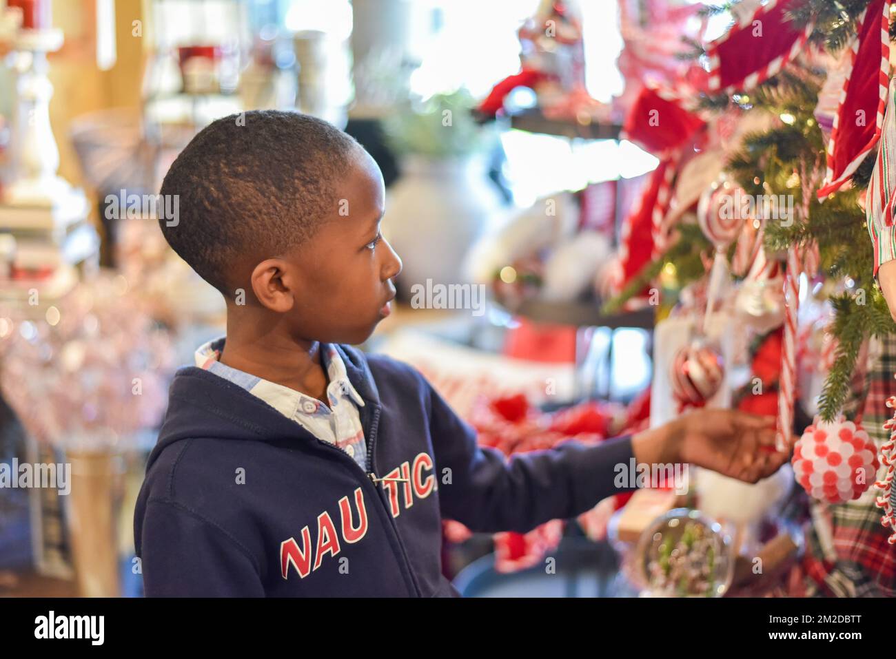 little boy at a retail store shopping for his family at Christmas time ...