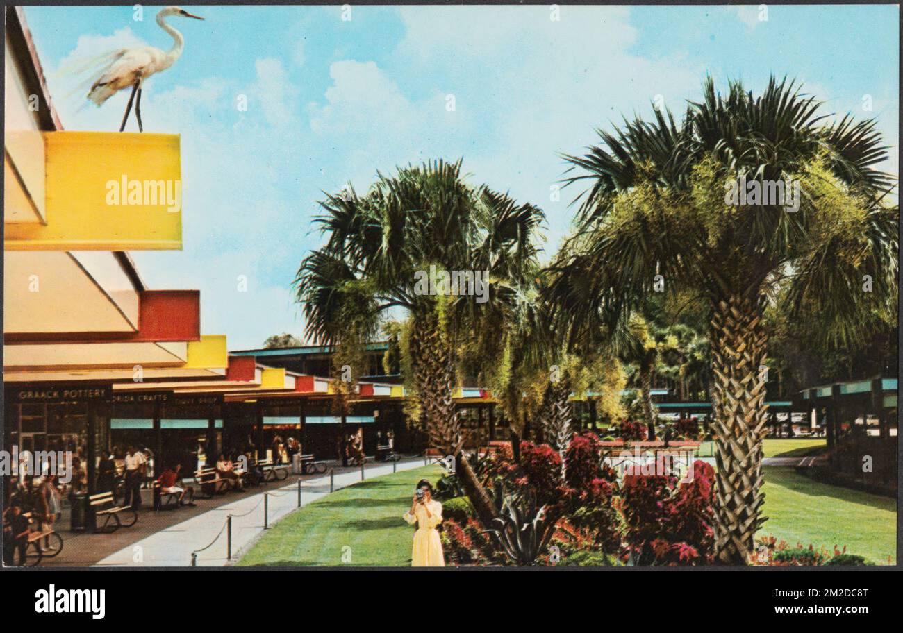 A covered promenade bordered by a colorful garden area is an ...