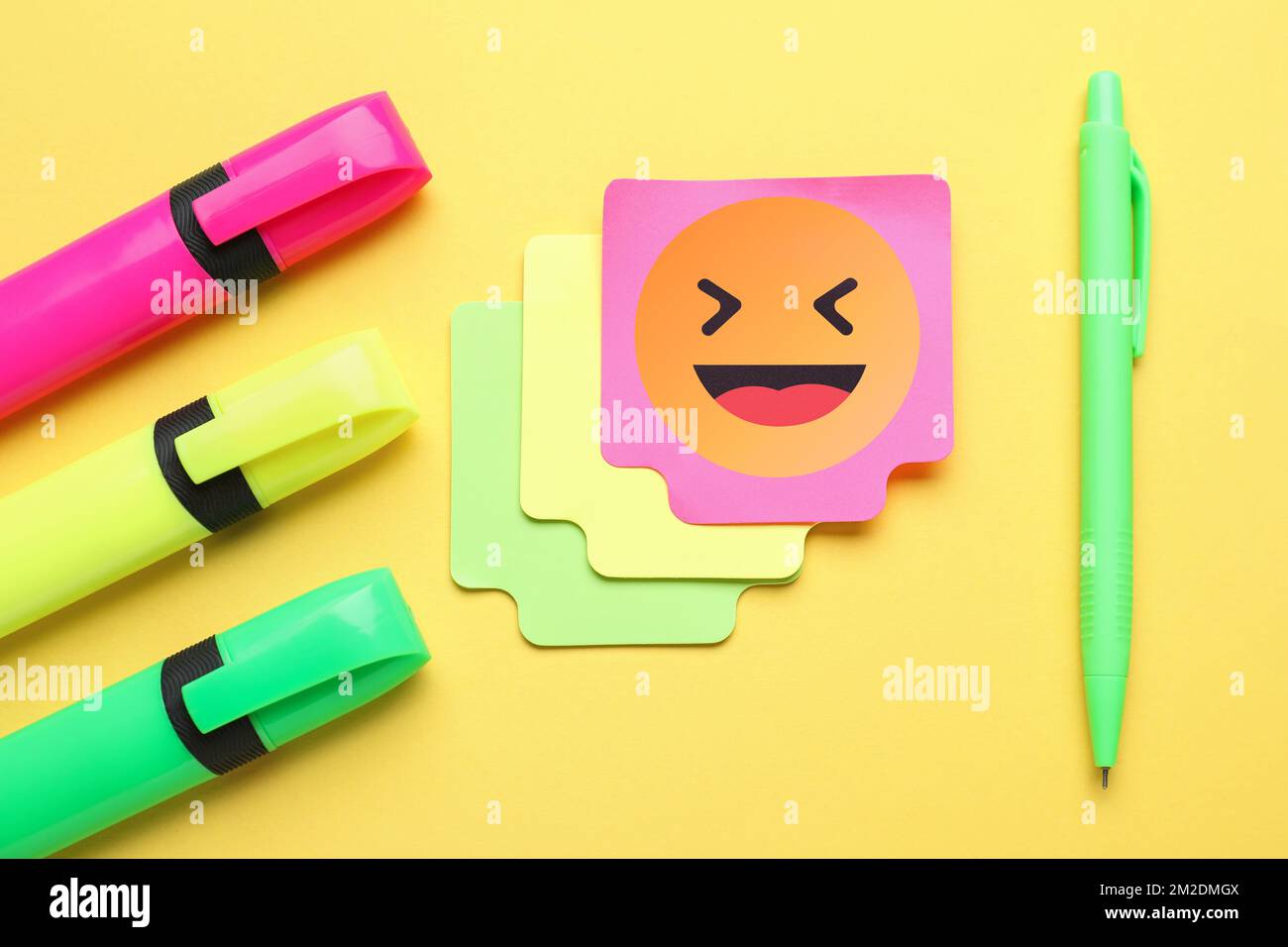 Sticky note with happy emoticon, markers and pen on color background ...
