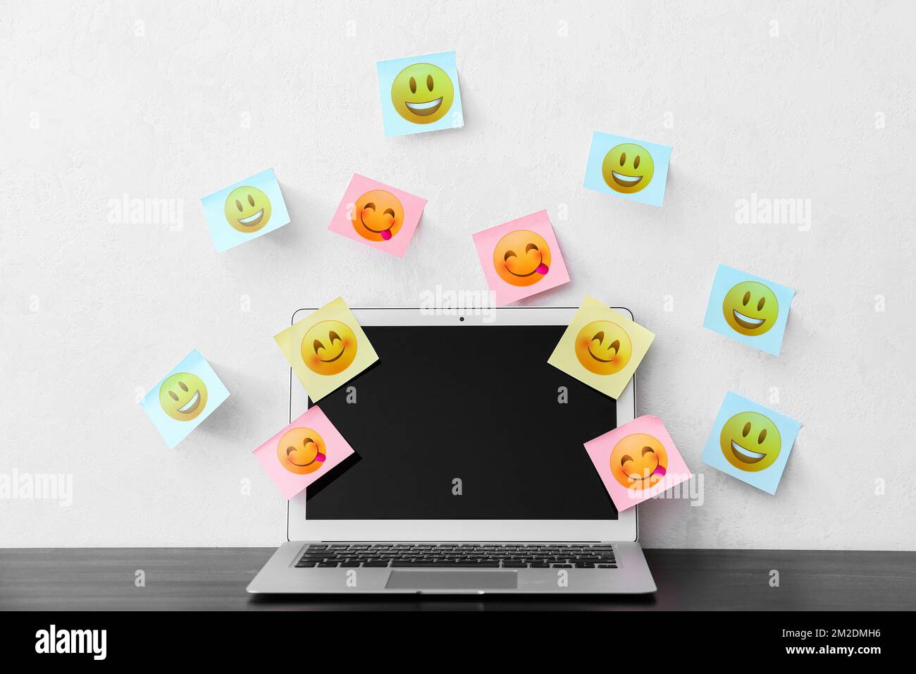 Modern laptop and different sticky note papers with drawn emoticons on ...