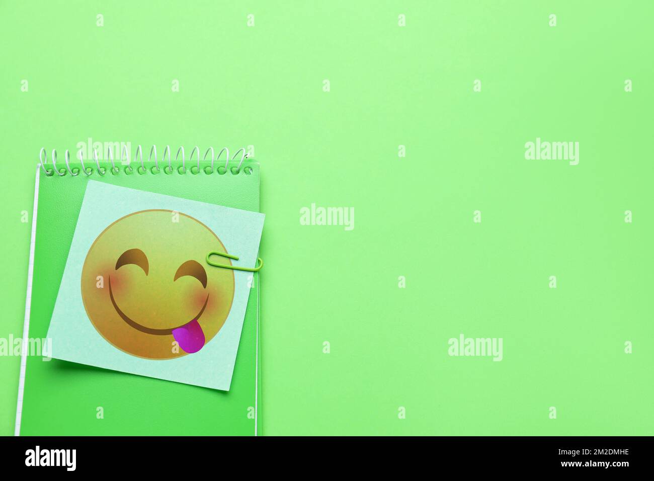 Sticky note with happy emoticon and notebook on green background with ...