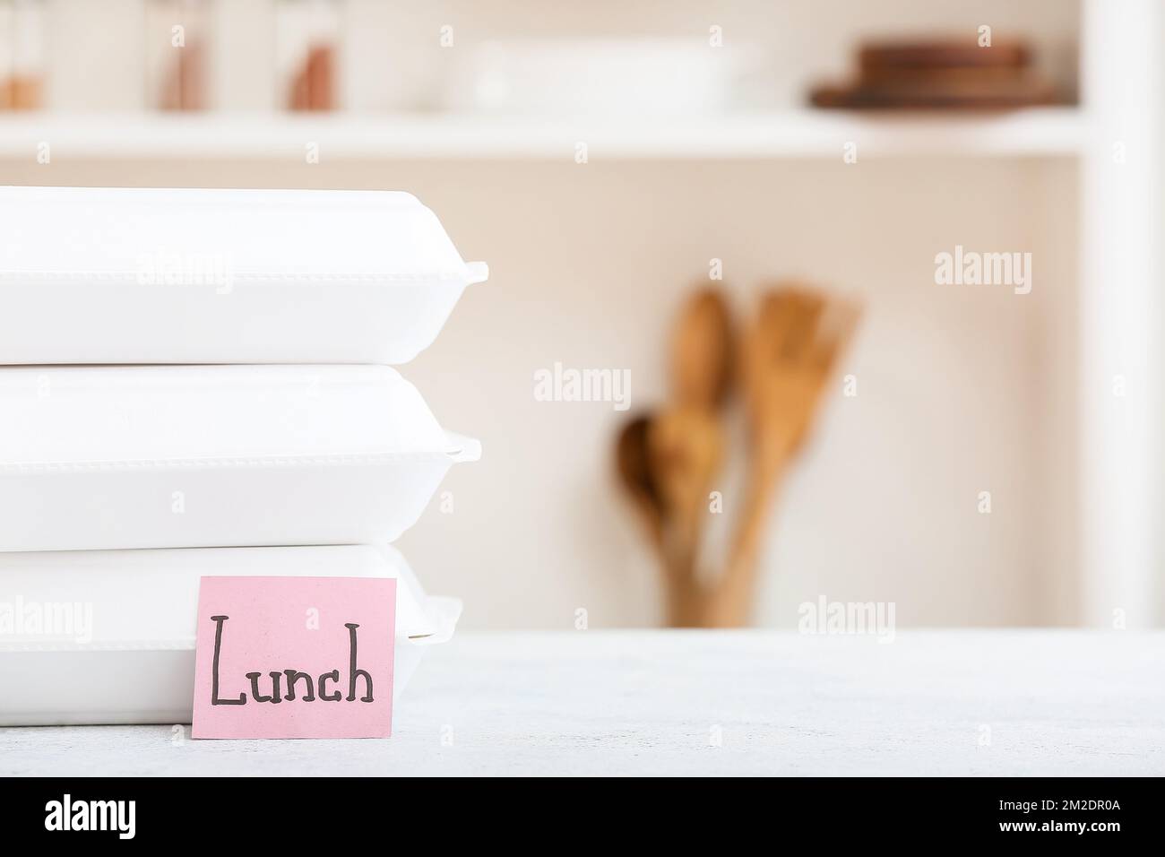 Food containers and sticky note with word LUNCH on white table Stock ...