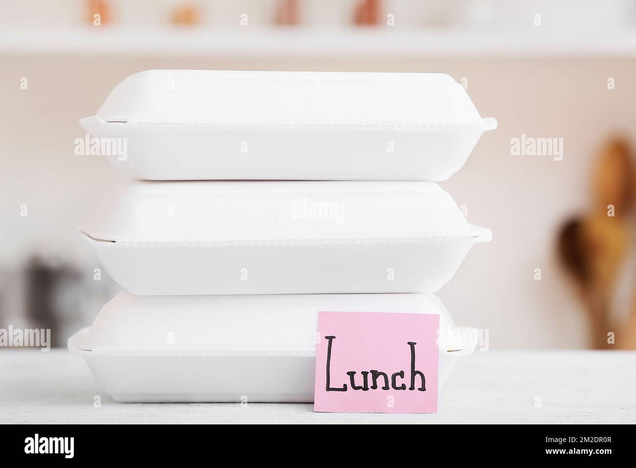 Food containers and sticky note with word LUNCH on white table Stock ...