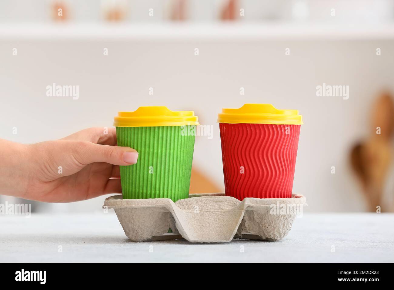 Woman taking paper cup with drink from holder on table Stock Photo - Alamy