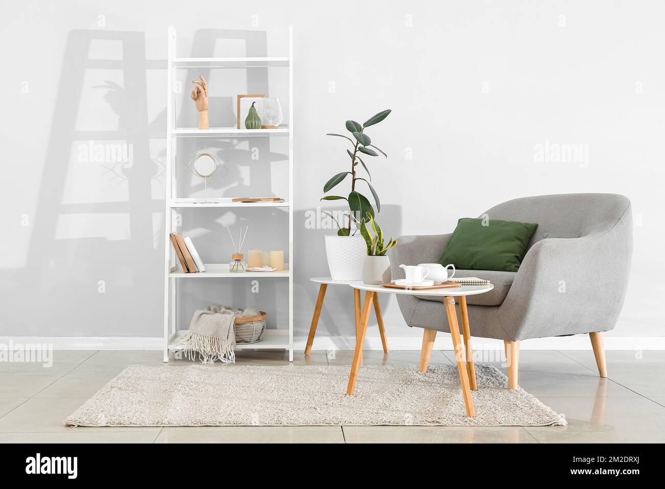 Interior of light living room with armchair, shelving unit, tables and ...