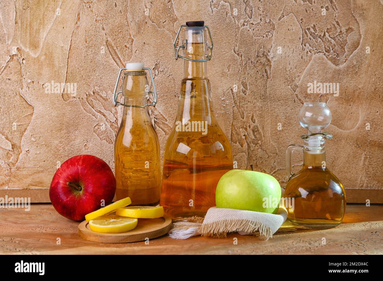 Bottles of apple cider vinegar and fruits on color table Stock Photo ...