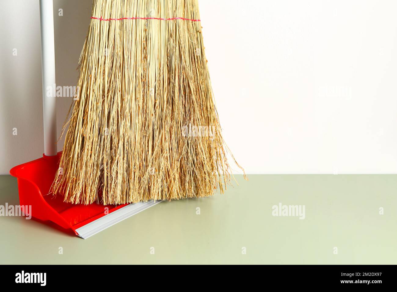 Red dustpan and broom near light wall, closeup Stock Photo - Alamy