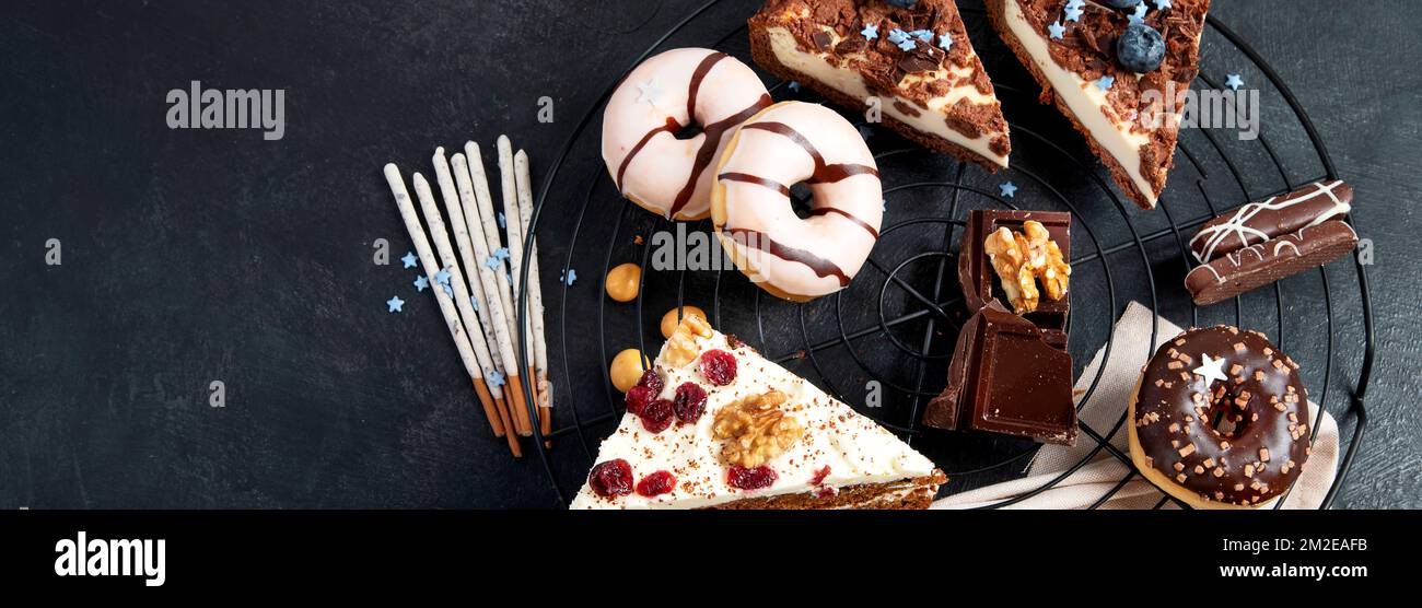 Table with various cookies, donuts, cakes, cheesecakes on dark ...
