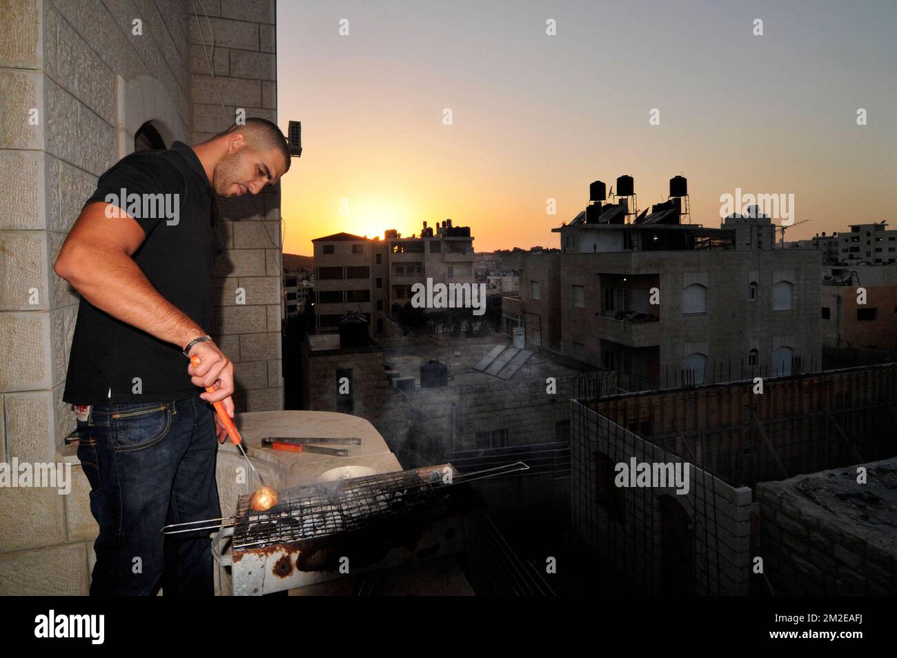 A Palestinian man grilling on his balcony in Beit Hanina in East ...