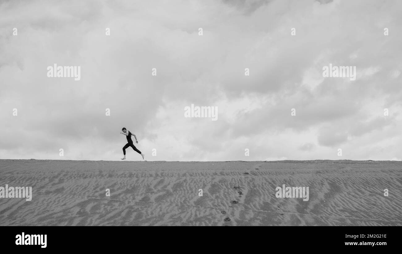 Lone man running on the sand through sandy desert on the horizon. Black ...