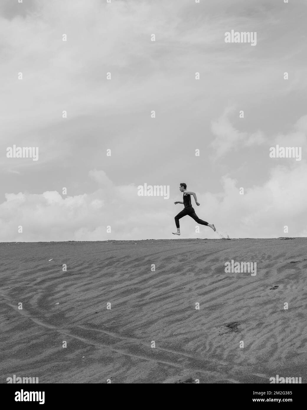 Lone man running on the sand through sandy desert on the horizon. Black ...