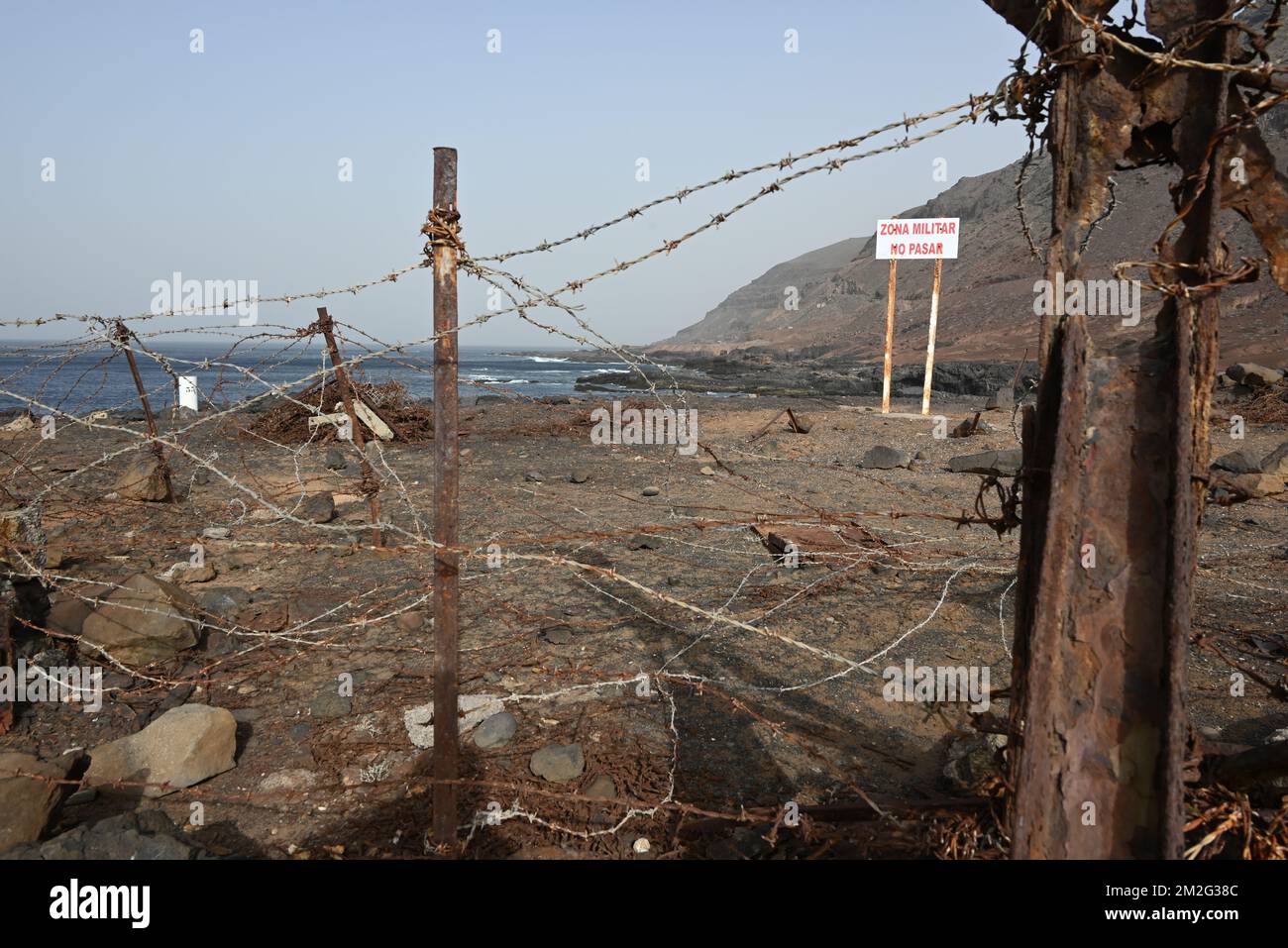 A barbed wire fence with a sign in the background, translation ...