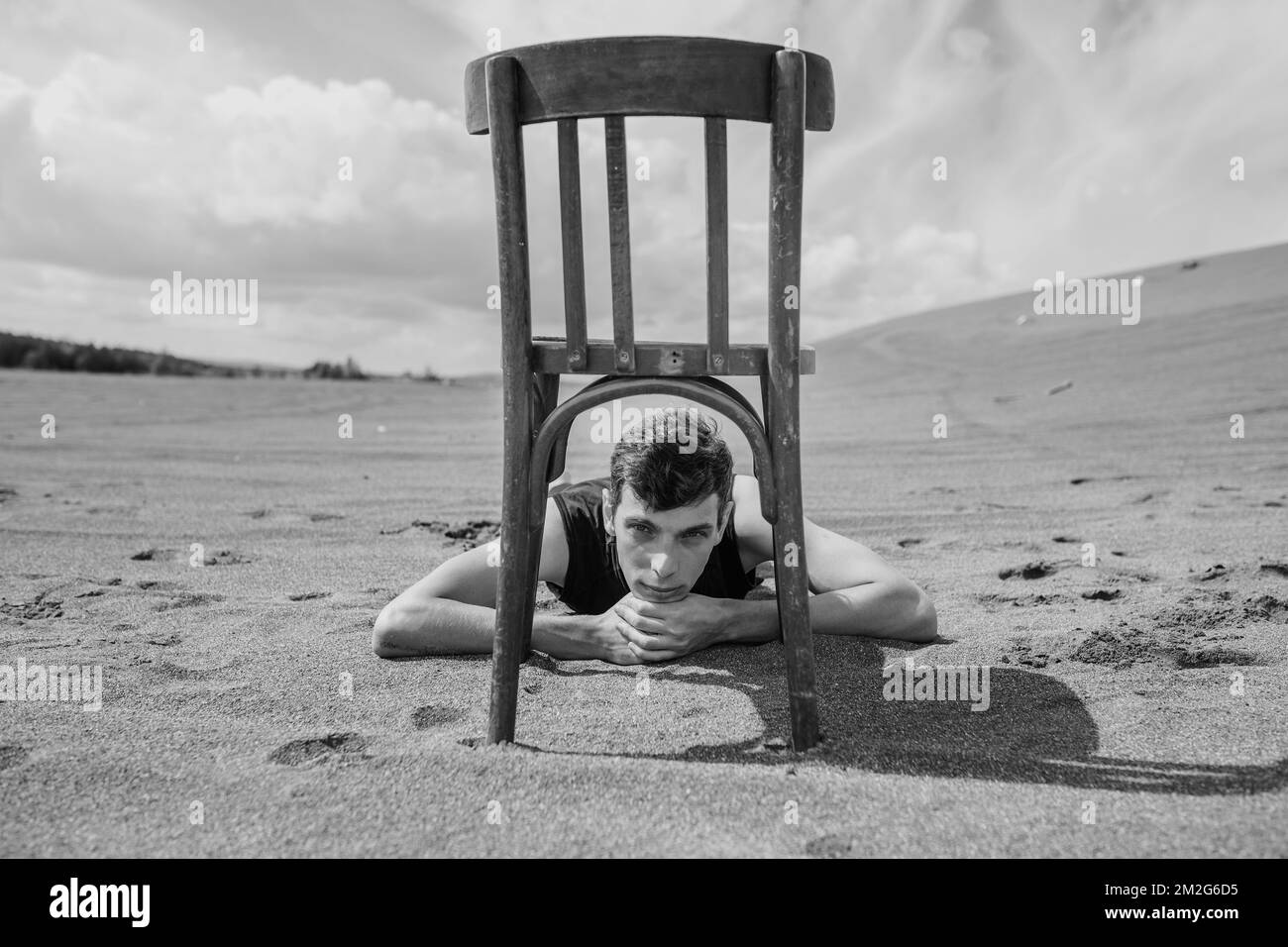 Man lying under chair in desert. black and white Stock Photo - Alamy