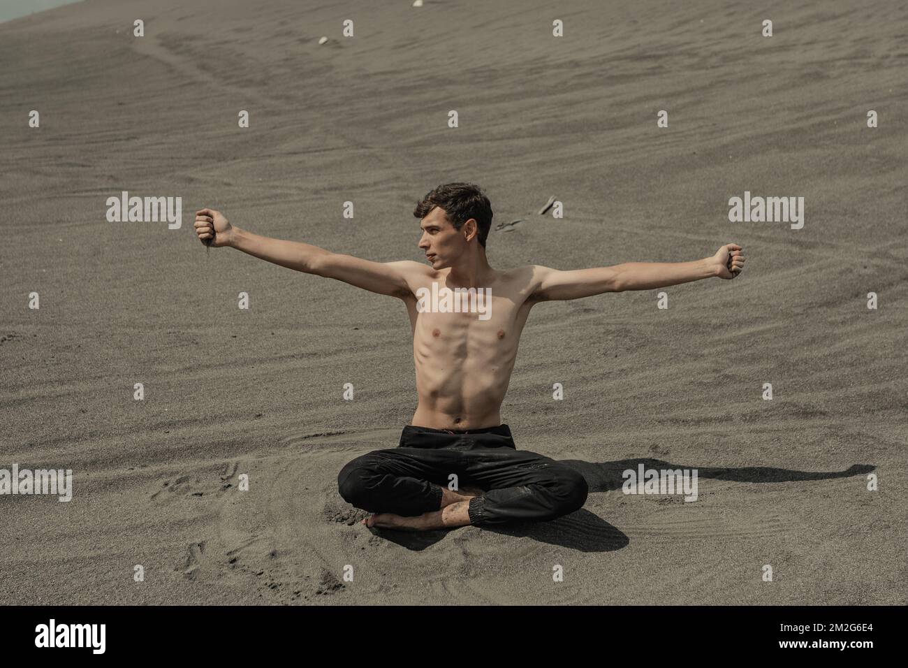 Man sitting on the sand dune and pouring sand through hand in desert ...