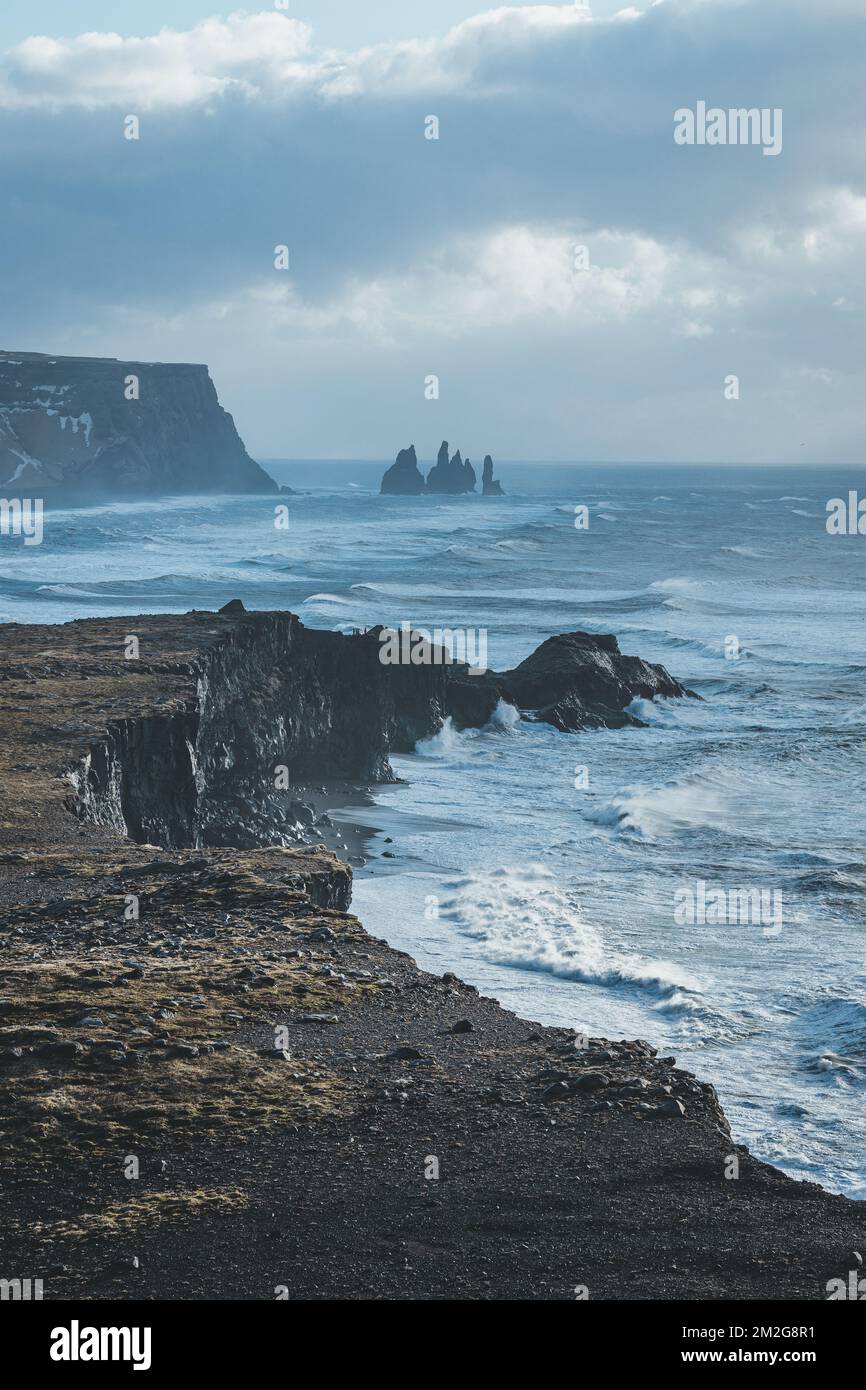 A vertical view of rocks by the rocky coast in the sea before a cloudy ...