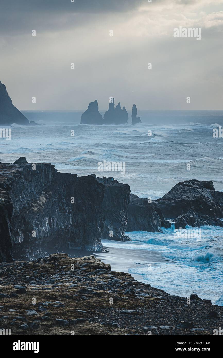 A vertical view of rocks by the rocky coast in the sea before a cloudy ...