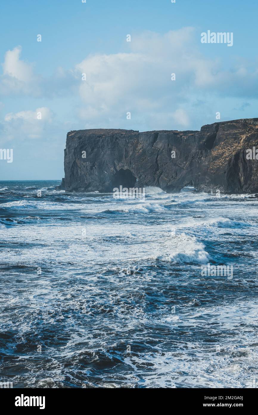 The vertical view of sea waves and a coastal cliff before the blue ...