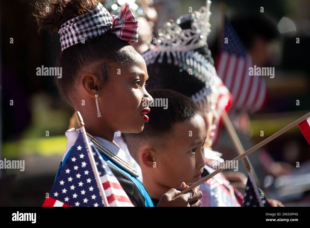 Hmong youth in traditional attire carry American flags in the entry ...