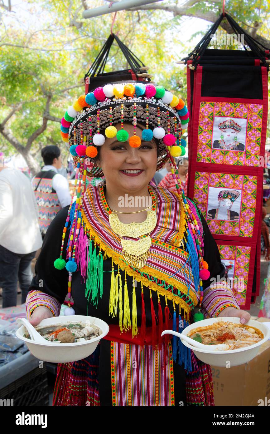 A woman in traditional attire holding two bowls of Hmong soup at the ...