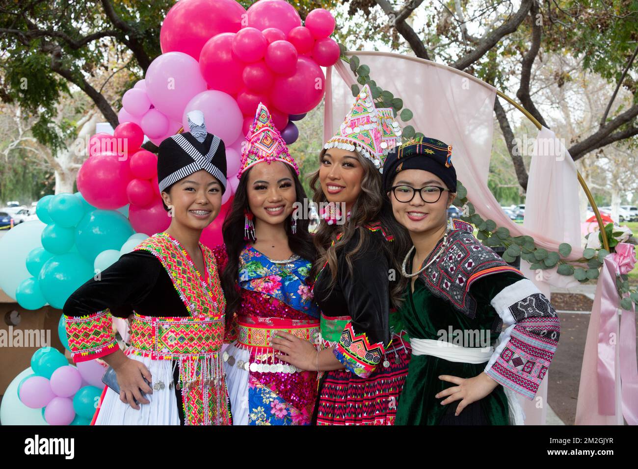 Young women in updated traditional costumes pose in front of a balloon ...
