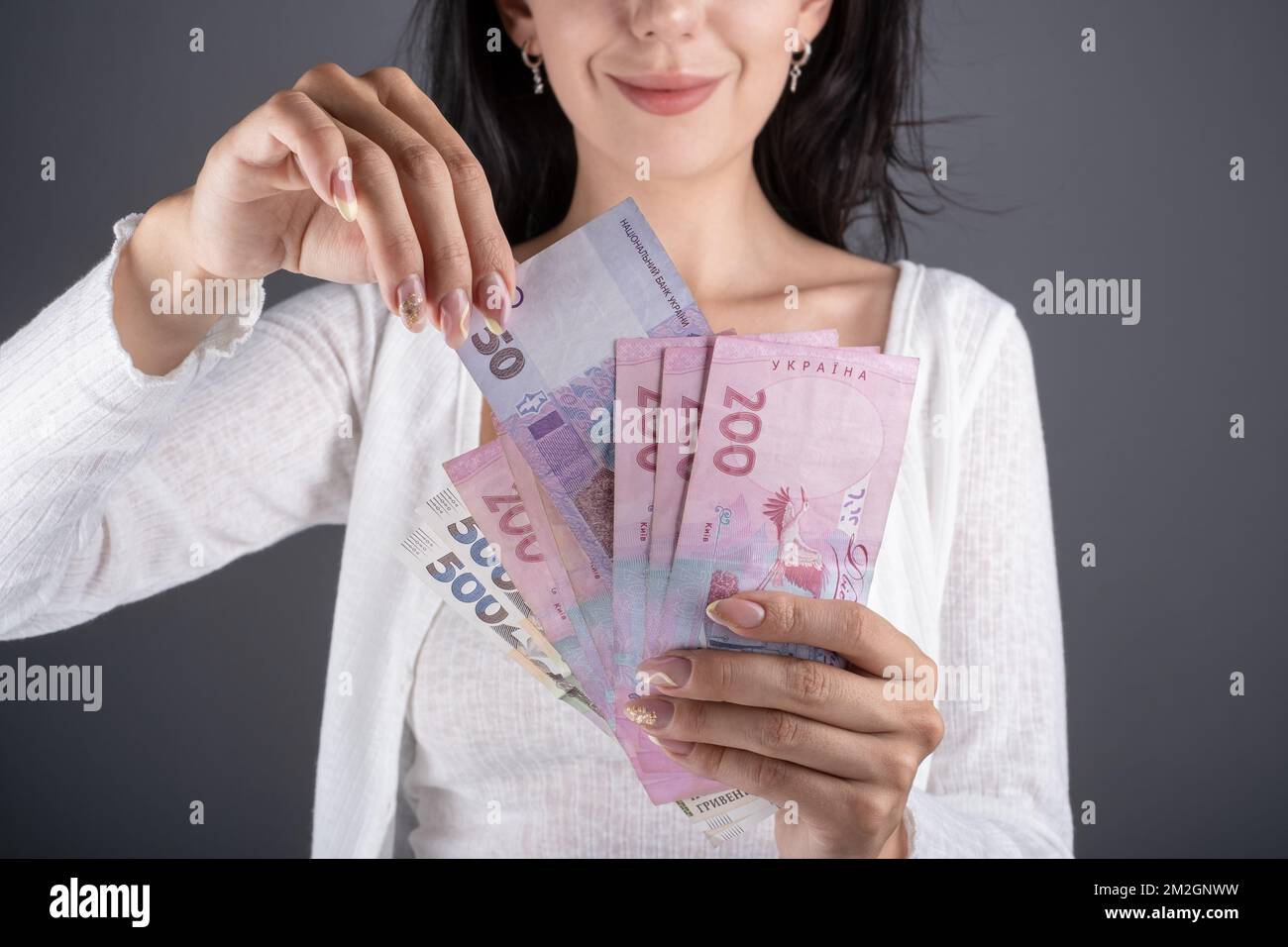 a woman pulls out a currency bancnote in nominal 50 UAH Ukrainian hryvnia. Woman hold Fan of ...