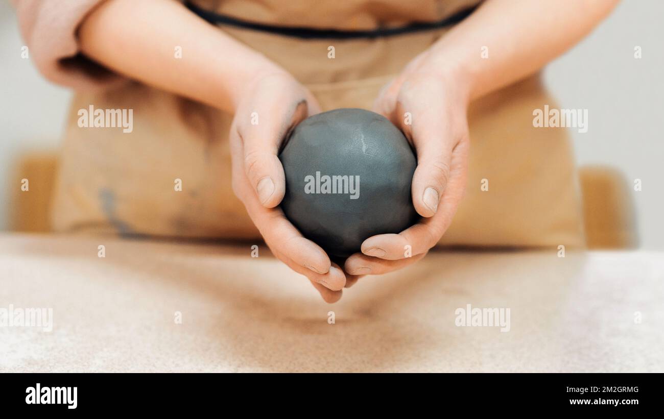 The master of sculpting pottery working in a studio. Holding a rounded ...