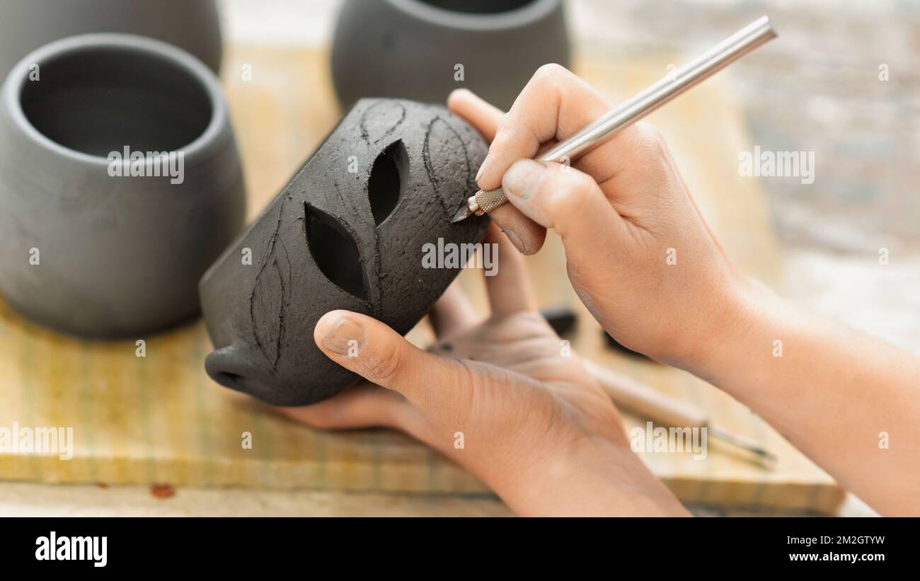 The master of sculpting pottery working in a studio. Cuts holes in ...