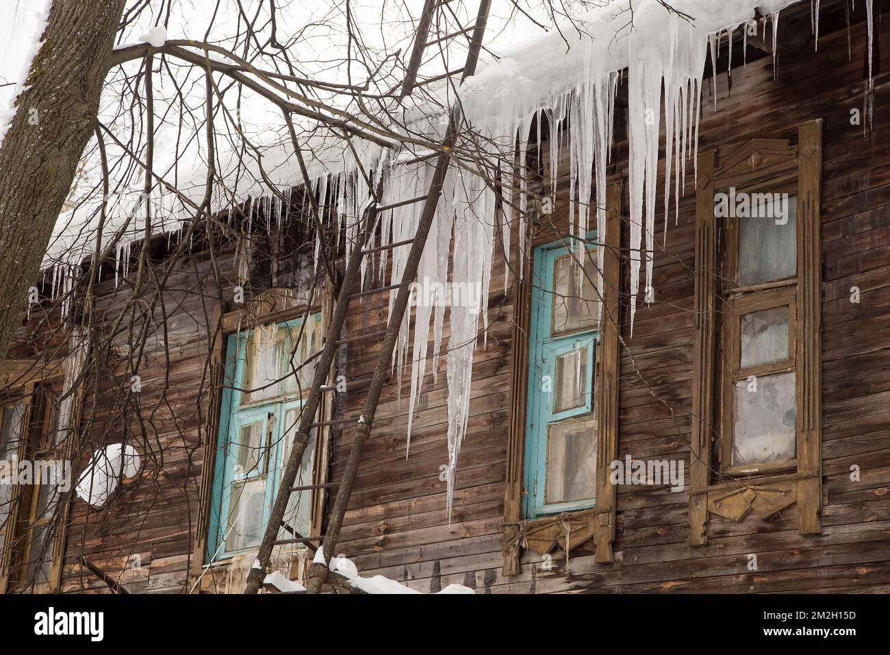 Sharp, frozen icicles hang on the edge of the roof, winter or spring ...