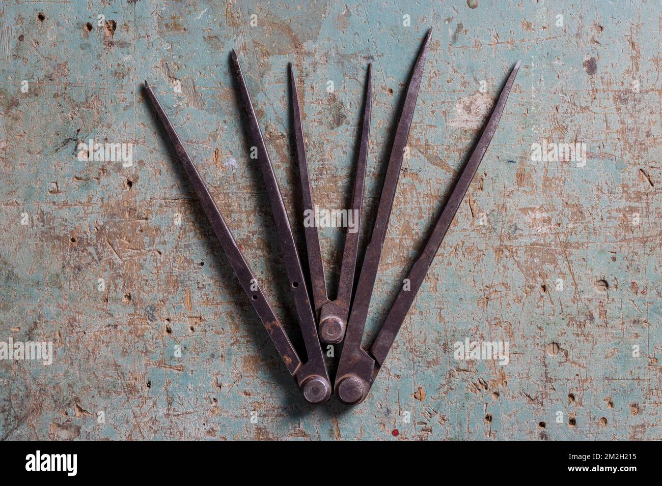 Three metal compass dividers for woodworking on a rustic surface flat ...