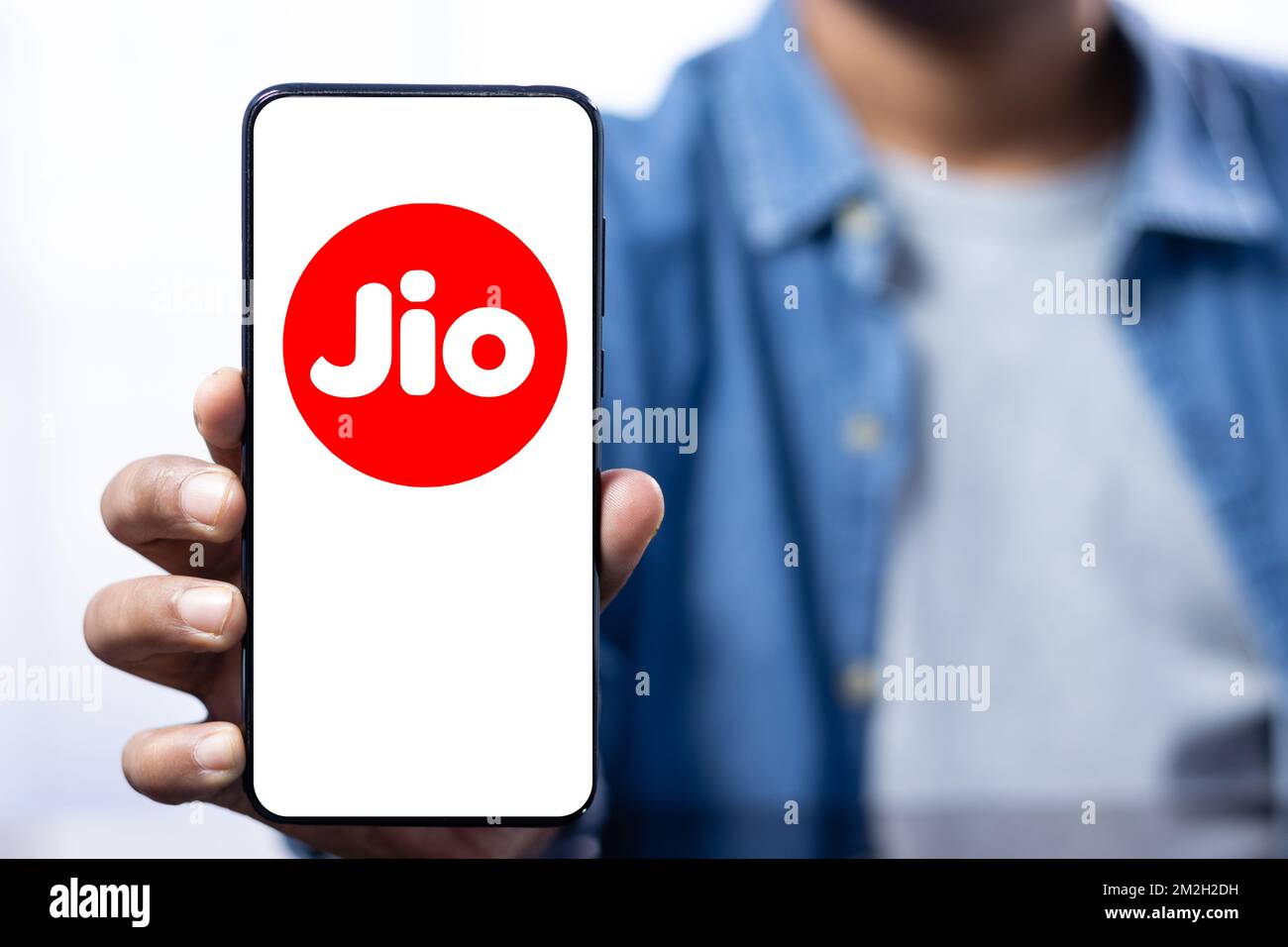 Close up of a smart phone screen with JIO logo held in hand by an ...