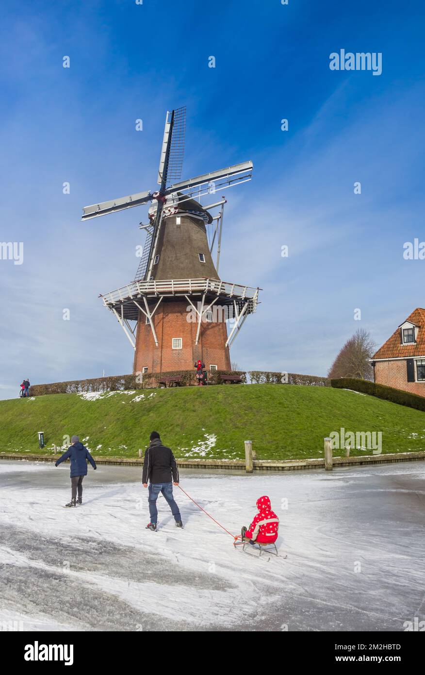 Man pulling a child on a sled on the frozen canal of Dokkum ...