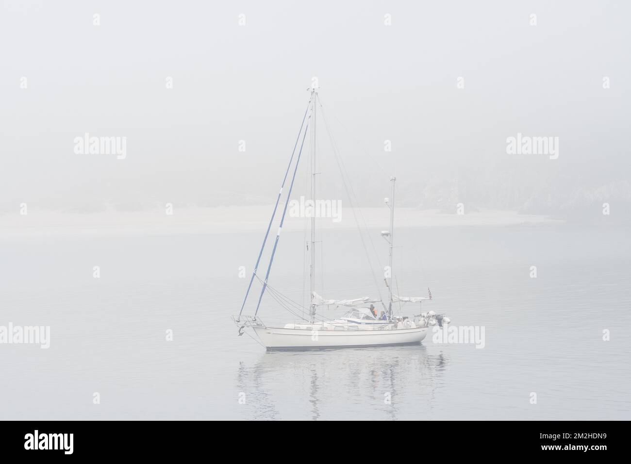 Sailboat / sailing boat / yacht with lowered sails anchored near beach ...
