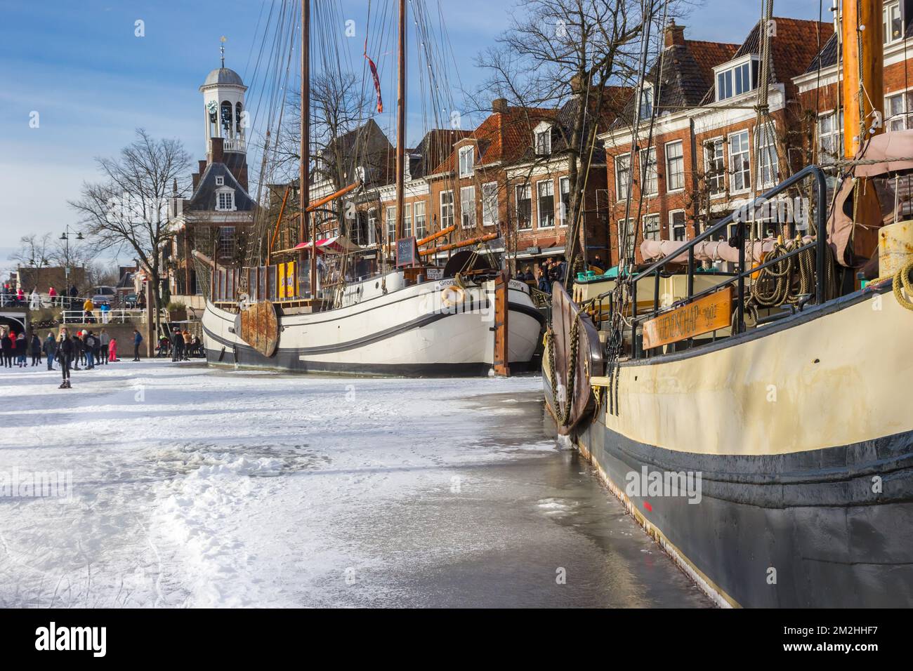Historic wooden sailing ships and town hall in winter in Dokkum ...