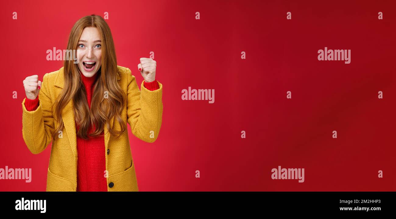 Studio shto of cheerful excited good-looking ginger girl in yellow coat ...