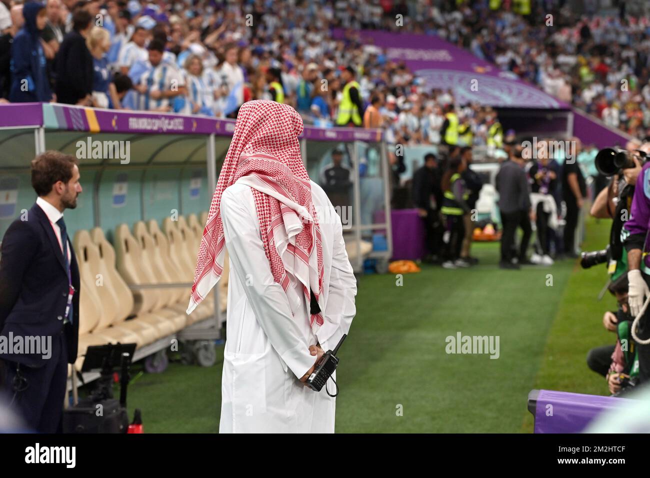 Qatar in traditional robe stands in front of the coach bench. Semi ...